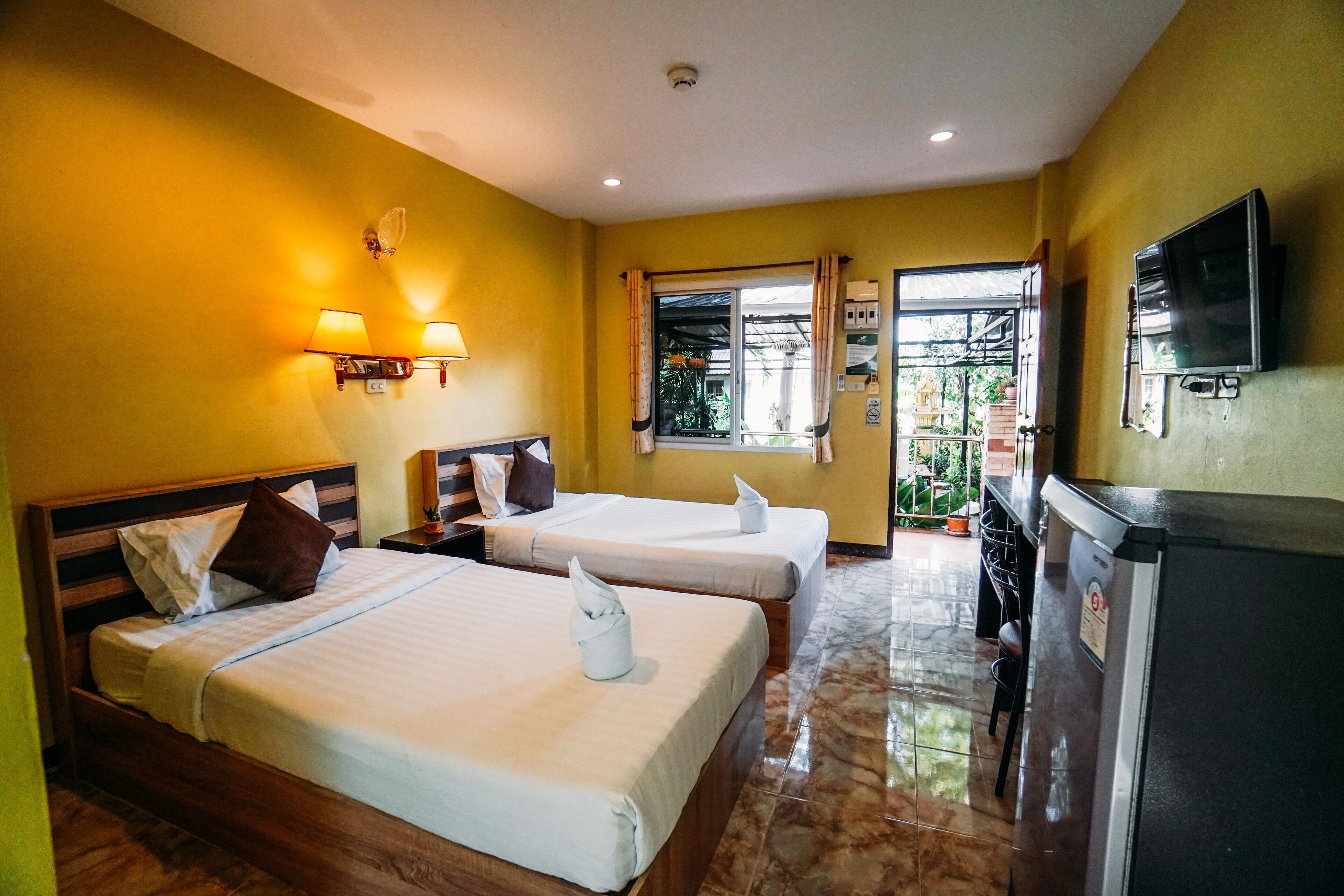 Quarto de hotel com duas camas, uma televisão e uma janela com cortinas.