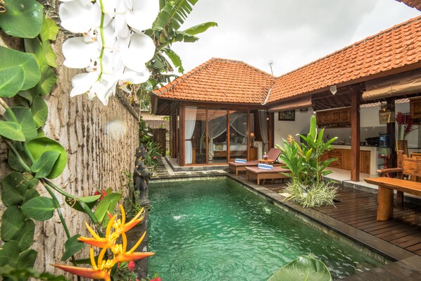 Uma área de piscina com deck de madeira, espreguiçadeiras e um espaço coberto para relaxar.