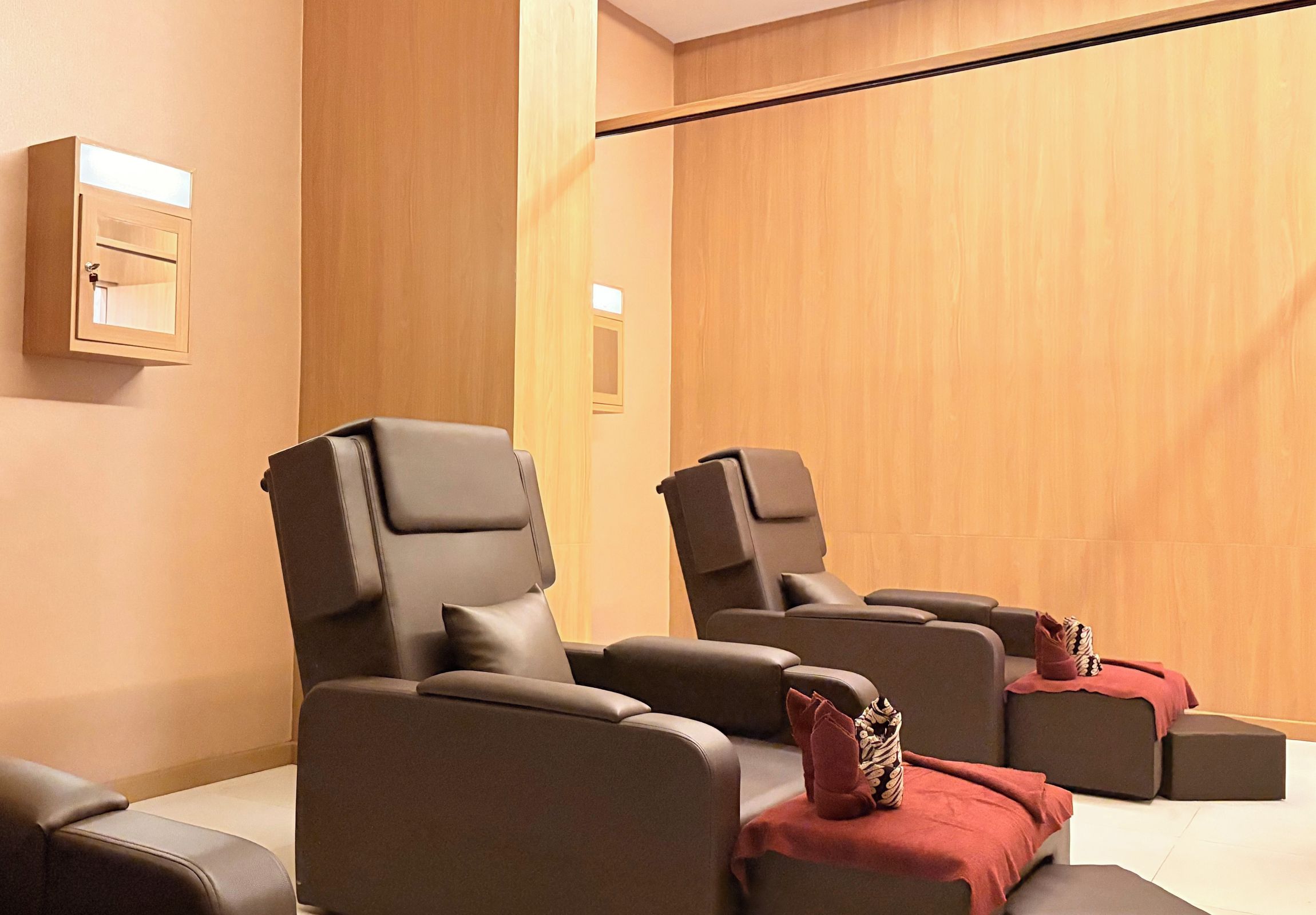 Quarto com duas cadeiras de massagem e parede de madeira.