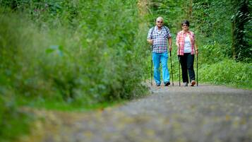 Duas pessoas caminham por um caminho rodeado por vegetação.