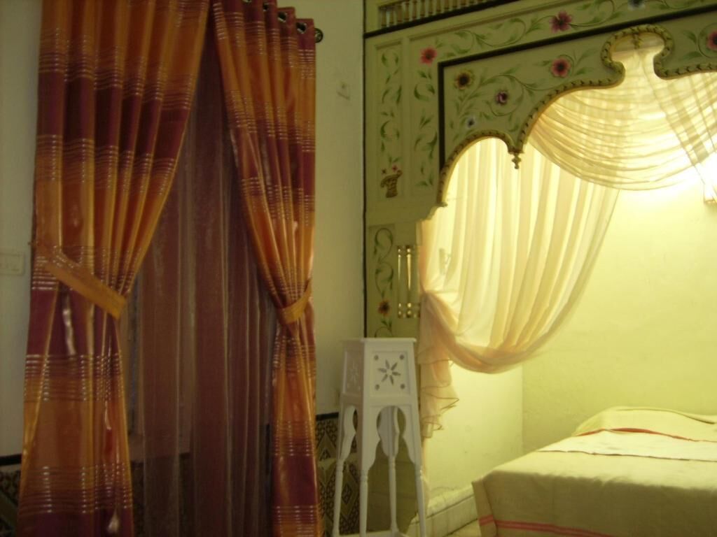 Quarto com cama, mesa de cabeceira e abajur decorativo.