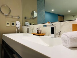 Casa de banho moderna com duas pias, secador de cabelo, toalha e espelho.