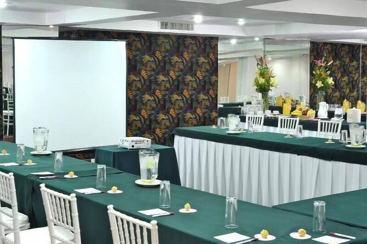 Uma sala de conferências com uma mesa comprida, cadeiras e um quadro branco.