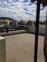 Uma varanda com vista para edifícios residenciais e uma colina.