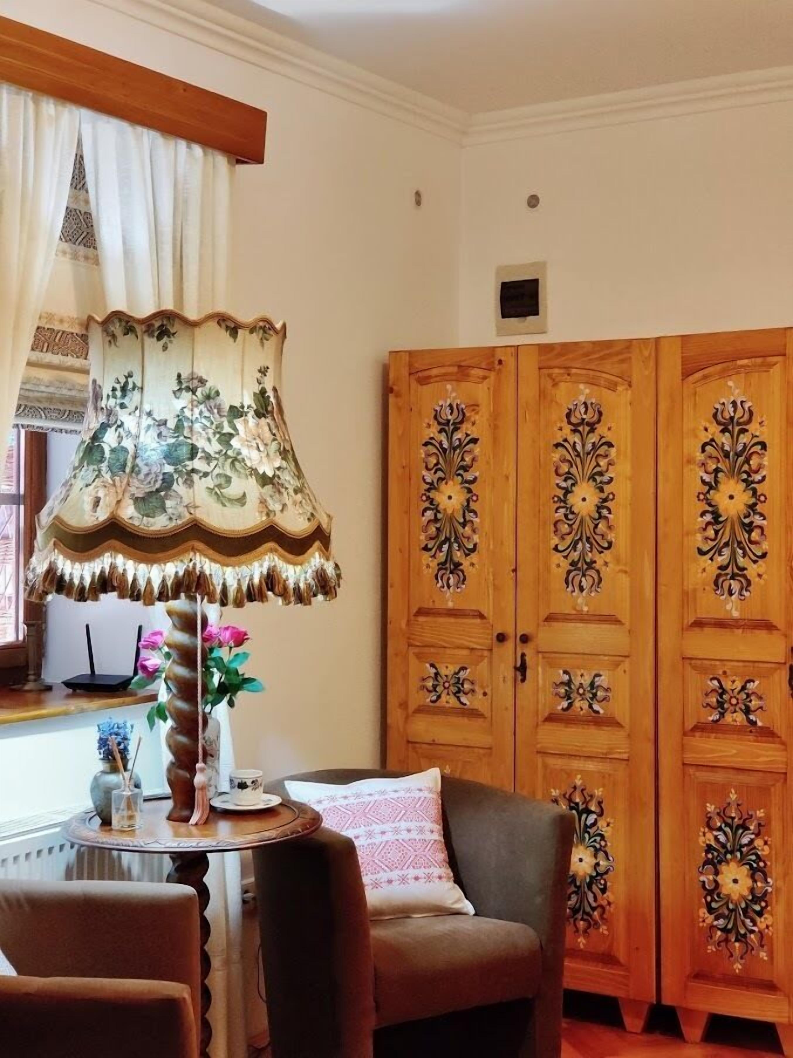 Quarto com guarda-roupa de madeira, uma mesa com luminária e uma cadeira.