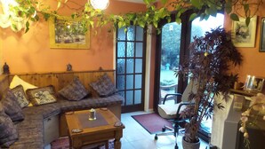 Um quarto acolhedor com um sofá de madeira, uma mesinha pequena e um vaso de planta.