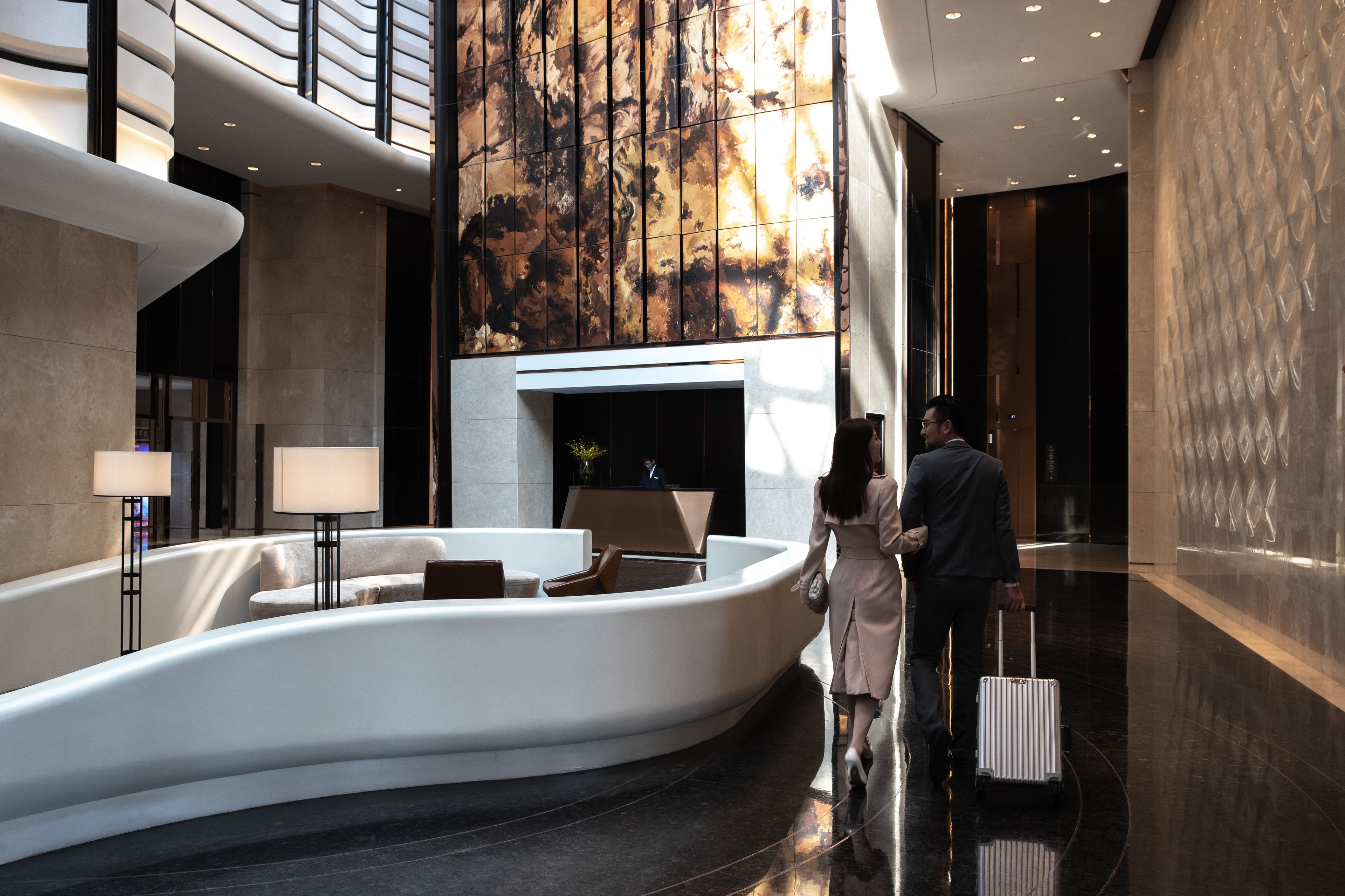 Um lobby moderno com uma recepção em balcão curvo, lareira e piso lustroso.