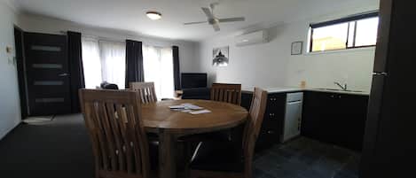 Um espaço compacto para viver, com área de refeições, cozinha compacta e ventilador de teto.
