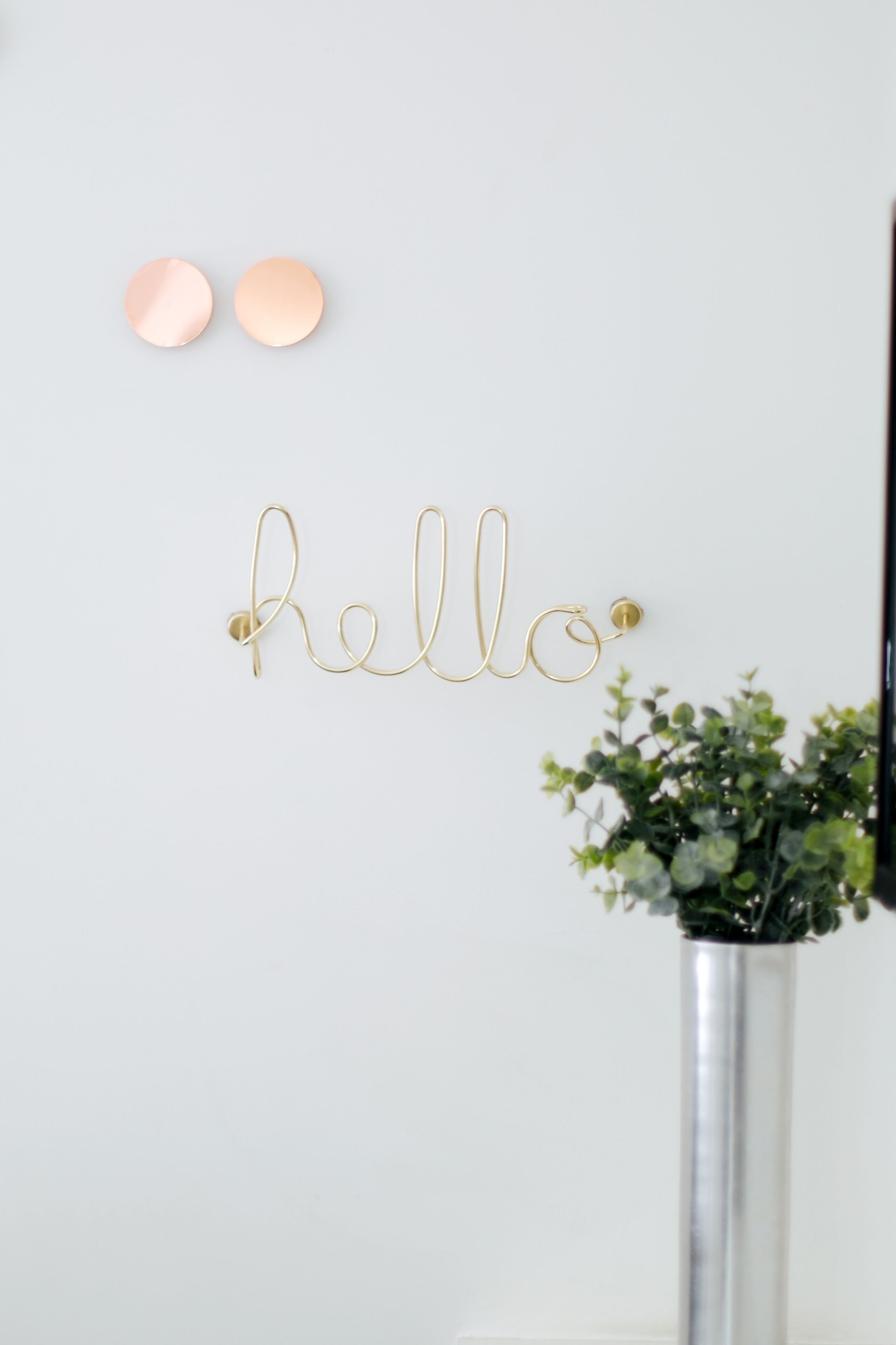 Uma parede com um letreiro que diz 'hello' e duas decorações circulares.