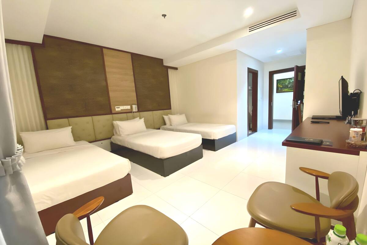 Quarto de hotel com duas camas, uma mesa de trabalho e uma área de estar.