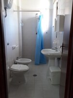 Um banheiro pequeno e limpo, com duas casas de banho, uma pia e um chuveiro.