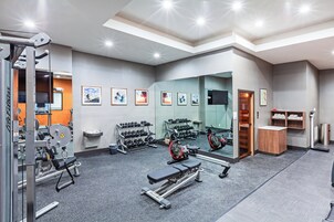 Uma academia com equipamentos de exercícios, espelho e sapateira.