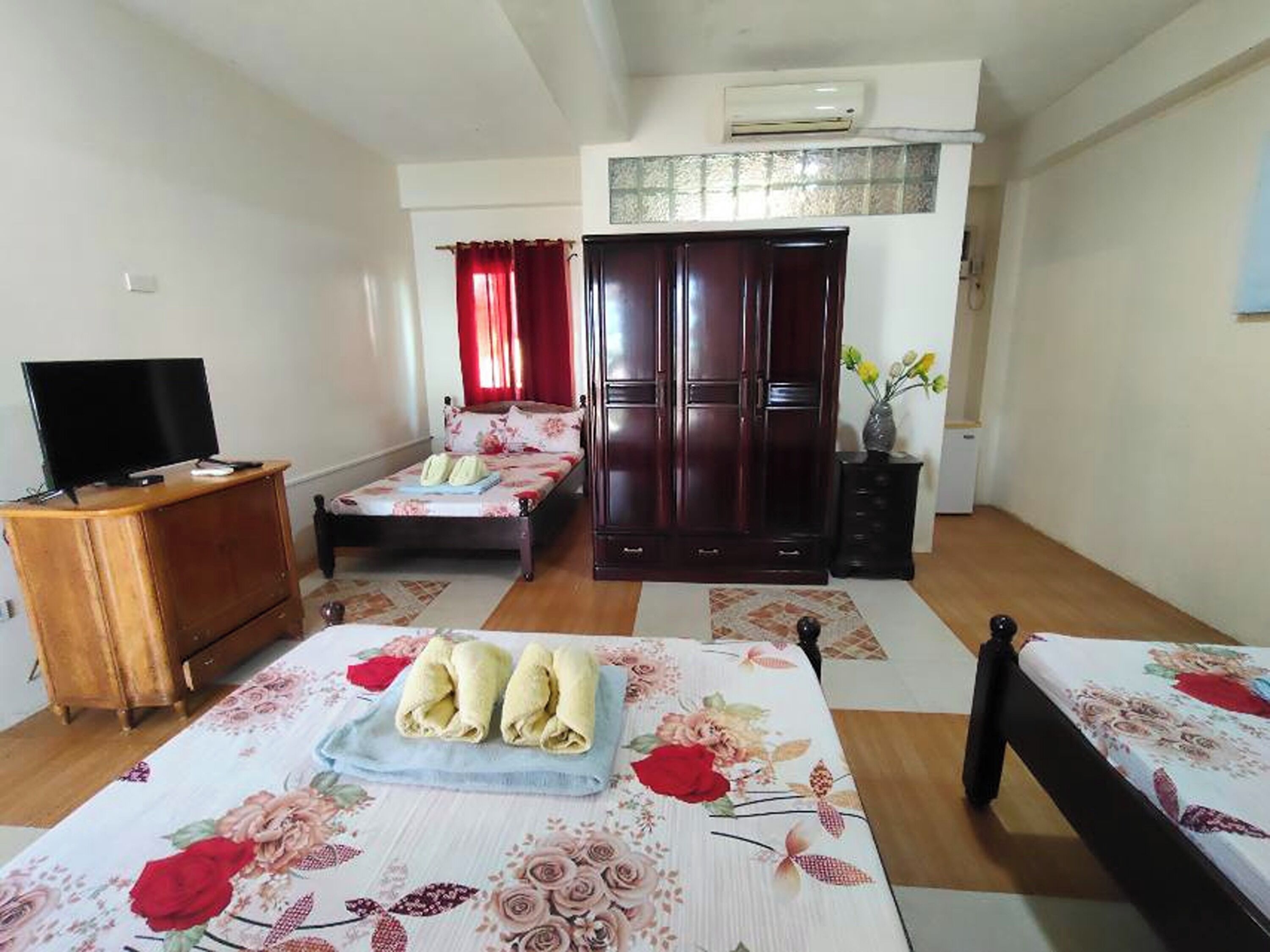 Quarto com cama, escrivaninha, guarda-roupa e televisão.