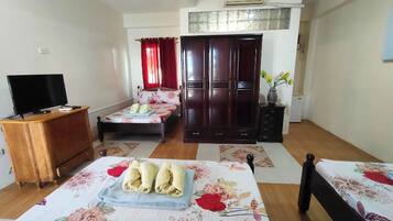 Quarto com cama, escrivaninha, guarda-roupa e televisão.
