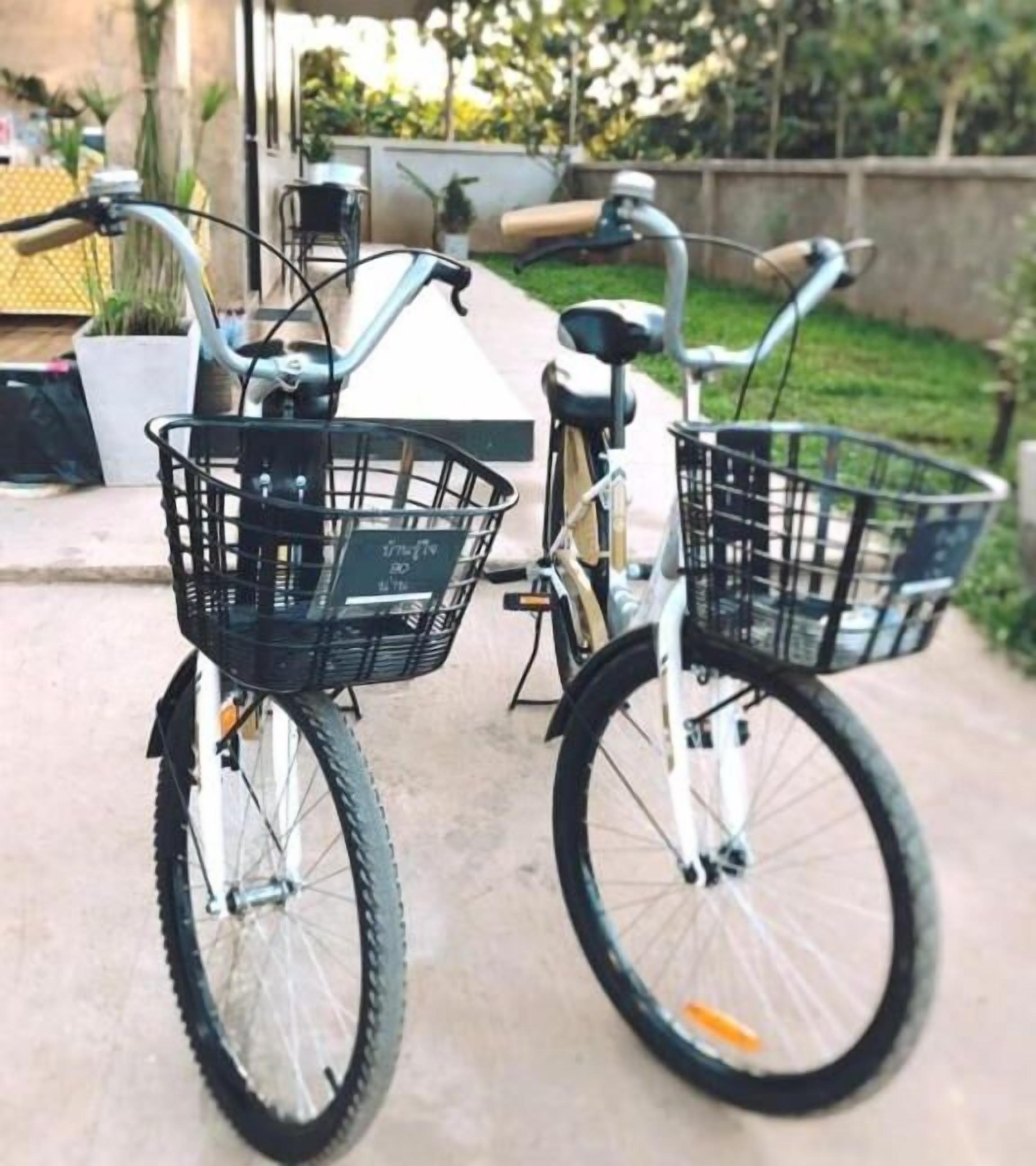 Duas bicicletas com cestas estacionadas em superfície de concreto.