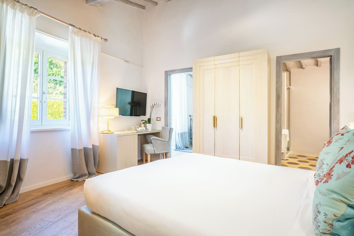 Quarto com cama, escrivaninha, cadeira, televisão e guarda-roupa.