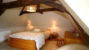 Um quarto de sótão aconchegante com uma cama de madeira, duas luminárias de cabeceira, uma pequena mesa de cabeceira e uma cadeira.