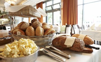 Uma mesa de buffet com diversos pães, doces e uma tigela de profiteroles.