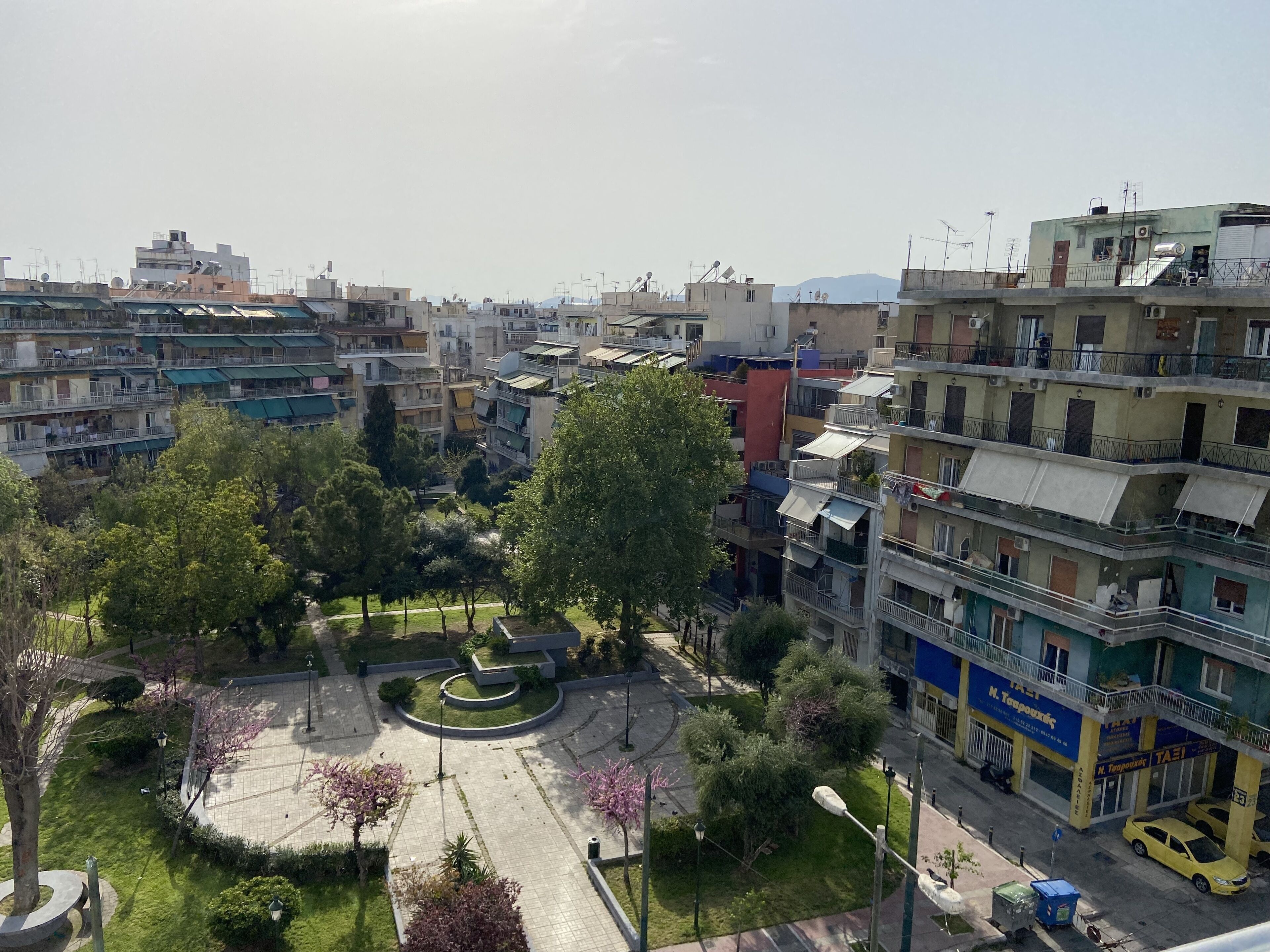 Edifício residencial com várias andares, varandas, uma praça circular central e áreas verdes ao redor.