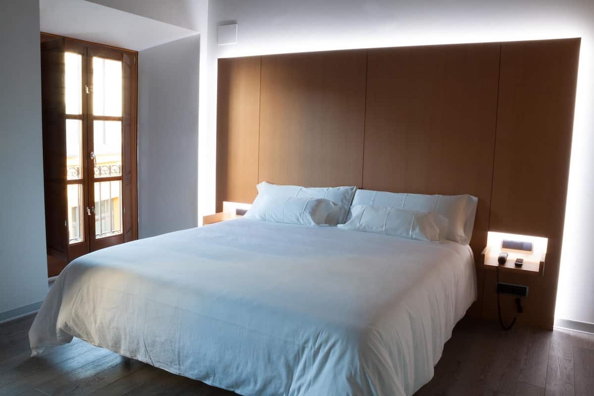 Quarto com uma cama grande, cabeceira de madeira, luminárias de cabeceira e uma janela com vista.