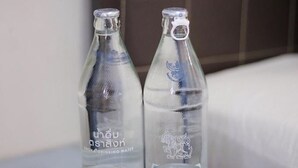 Duas garrafas de vidro transparentes com água e um pequeno recipiente de vidro sobre uma mesa.