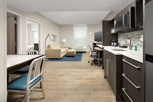 Quarto de hotel moderno com cozinha compacta, área de jantar e sala de estar.