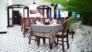 Um restaurante com toalhas de mesa xadrez, cadeiras de madeira e chão de azulejos.