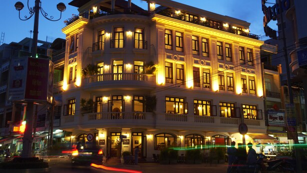 Um hotel de vários andares com varandas, janelas iluminadas e vista para a rua.