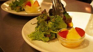 Um prato com salada e uma pequena tigela de fruta.