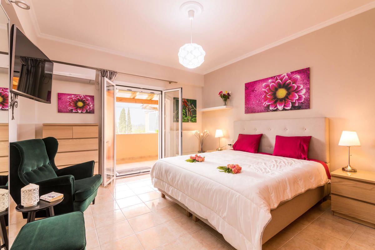 Quarto de hotel com cama, escrivaninha, cadeira, televisão e varanda.