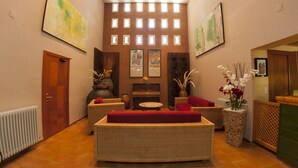 Um hall com móveis de vime, lareira e obras de arte nas paredes.