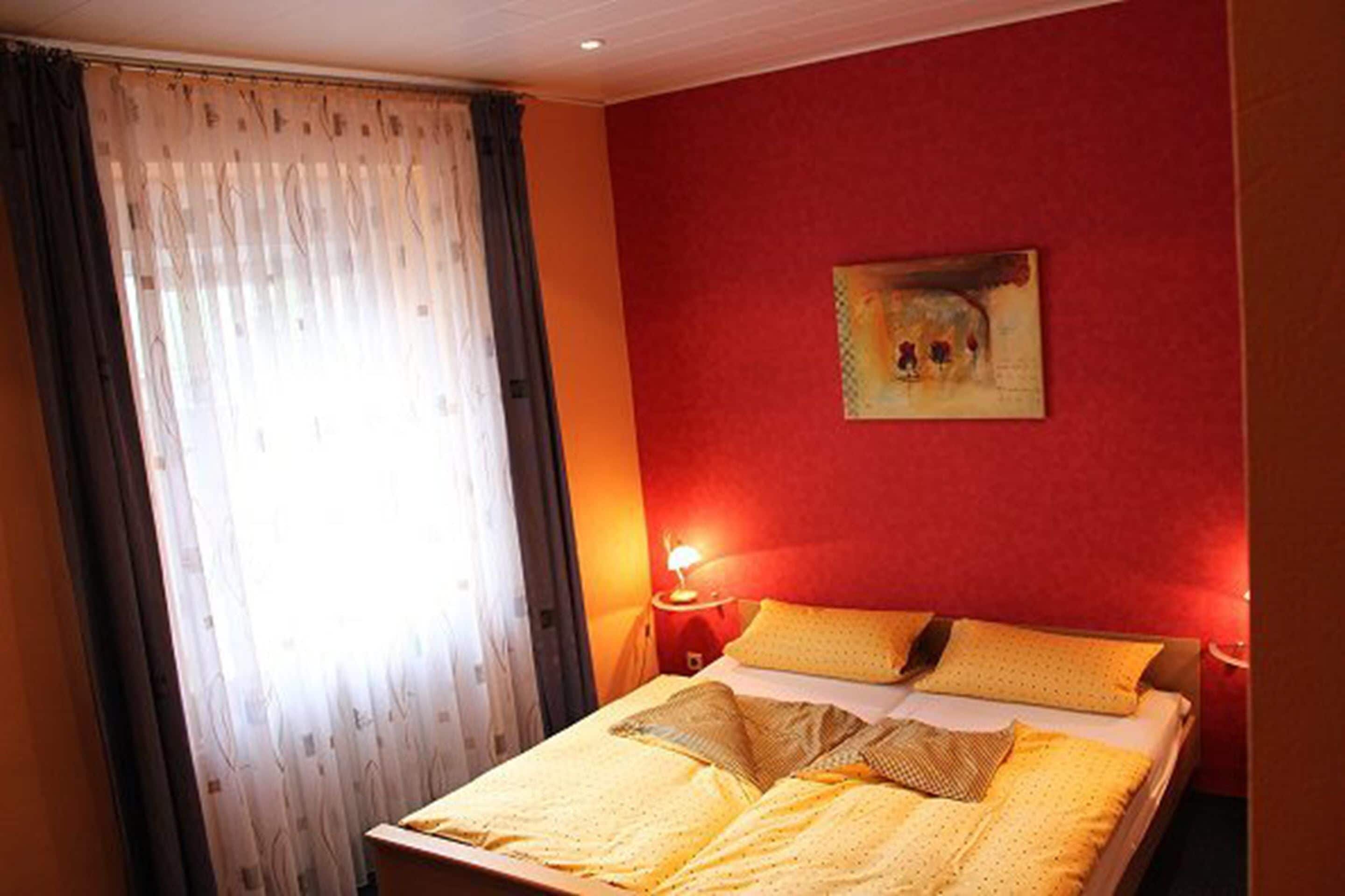 Um quarto com uma cama, um quadro na parede e uma janela com cortinas.