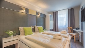 Quarto de hotel moderno com uma cama grande, uma escrivaninha e uma cadeira.