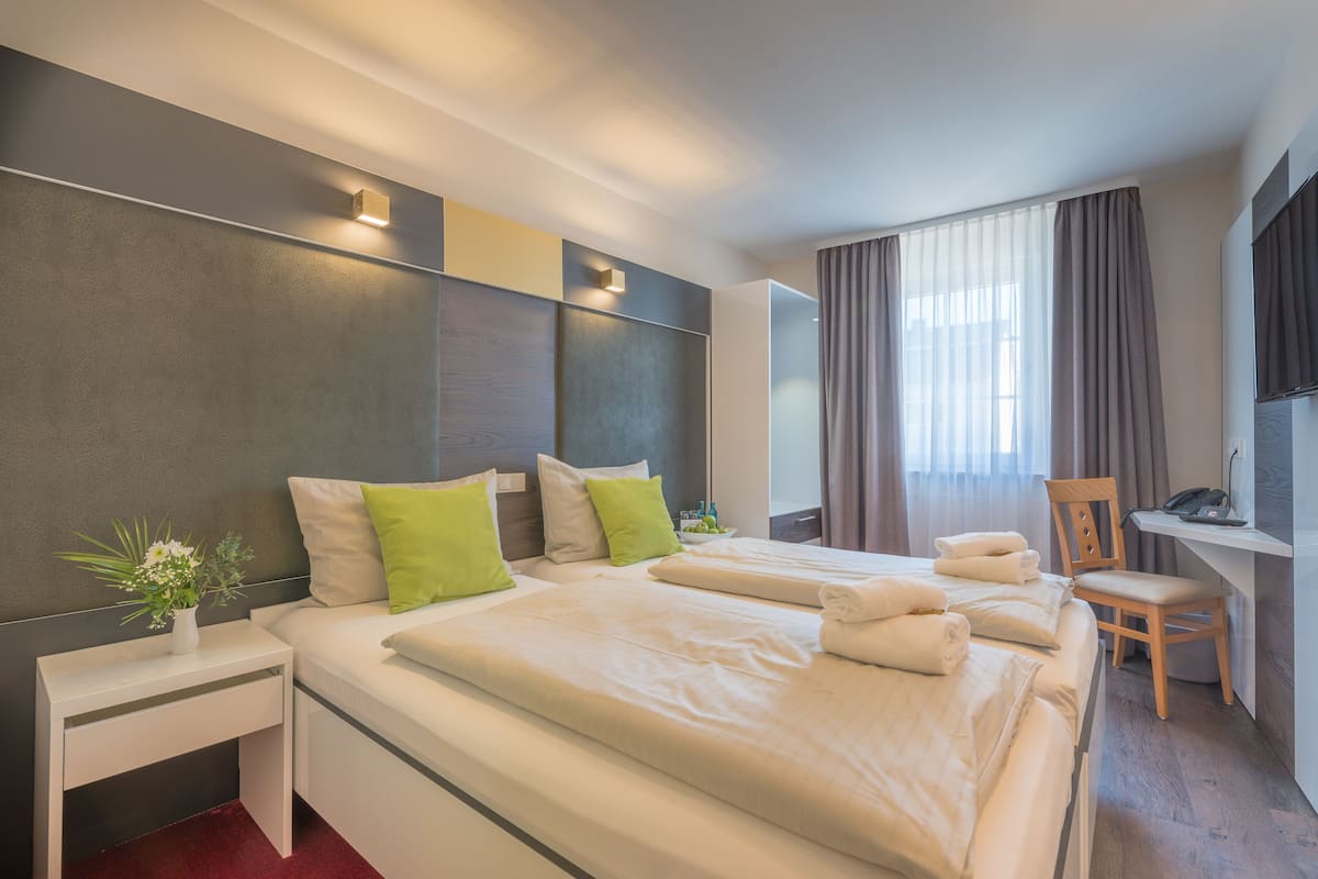 Quarto de hotel moderno com uma cama grande, uma escrivaninha e uma cadeira.