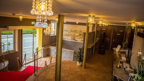 Um saguão de hotel com tapete vermelho, balcão de recepção e um mural na parede.