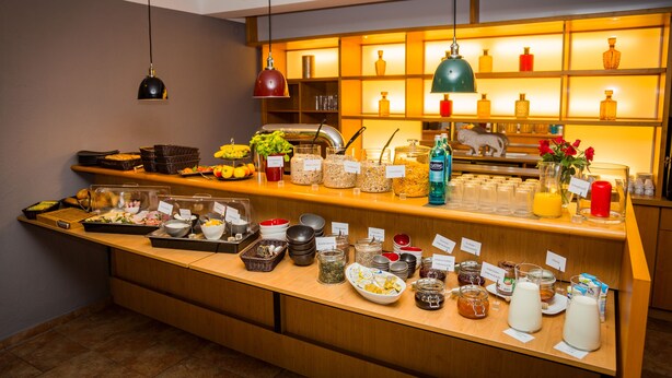 Buffet com diversos alimentos e bebidas, incluindo frutas, saladas e acompanhamentos.