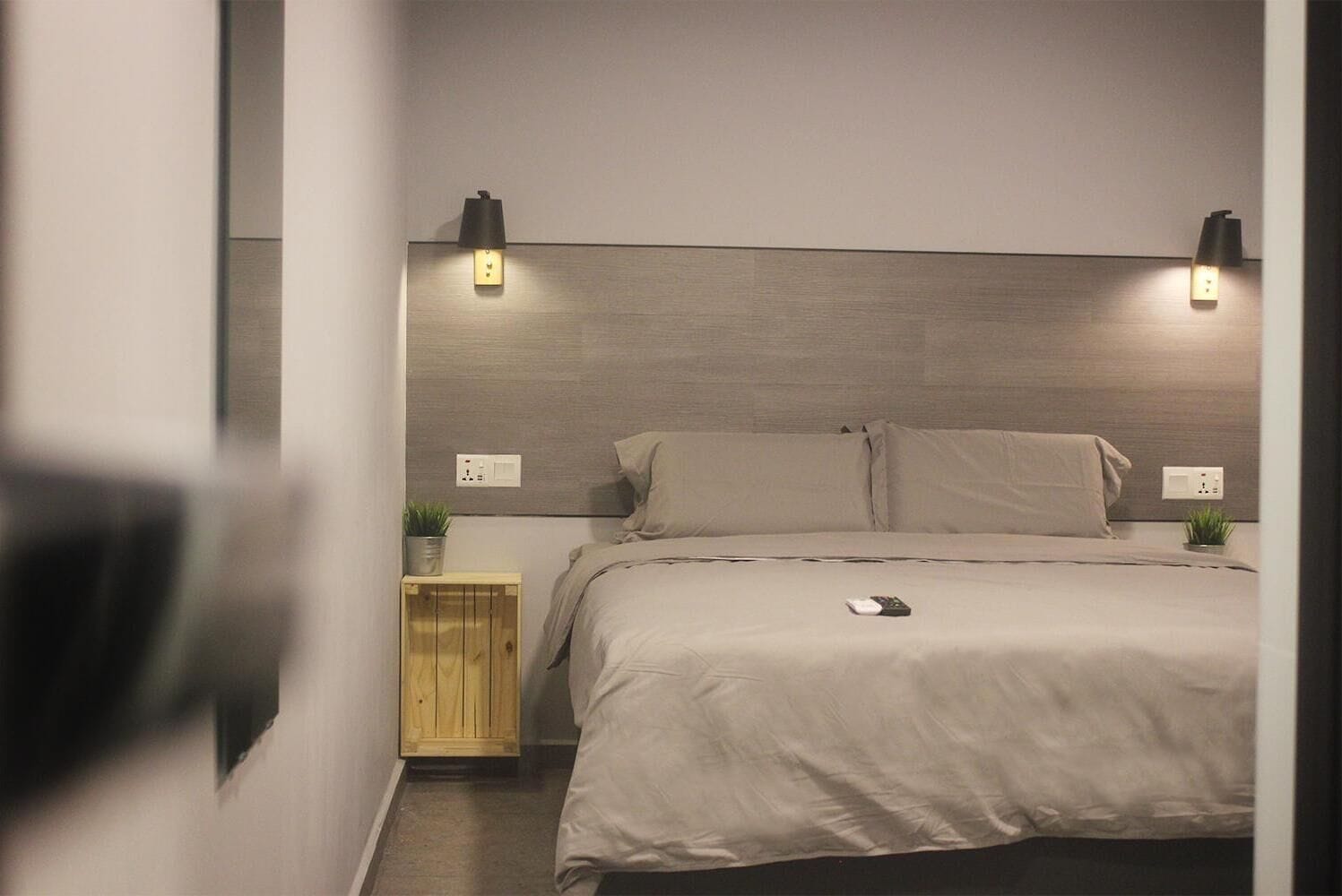 Quarto moderno com uma cama grande, duas mesas de cabeceira com abajures e um pequeno armário de madeira.