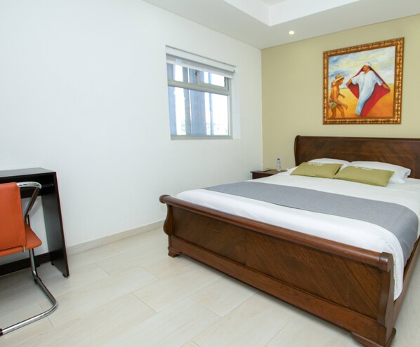 Quarto com cama de madeira, uma escrivaninha e uma cadeira.
