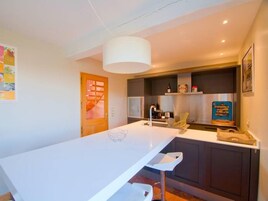 Uma cozinha moderna com uma ilha grande, armários escuros e um lustre.