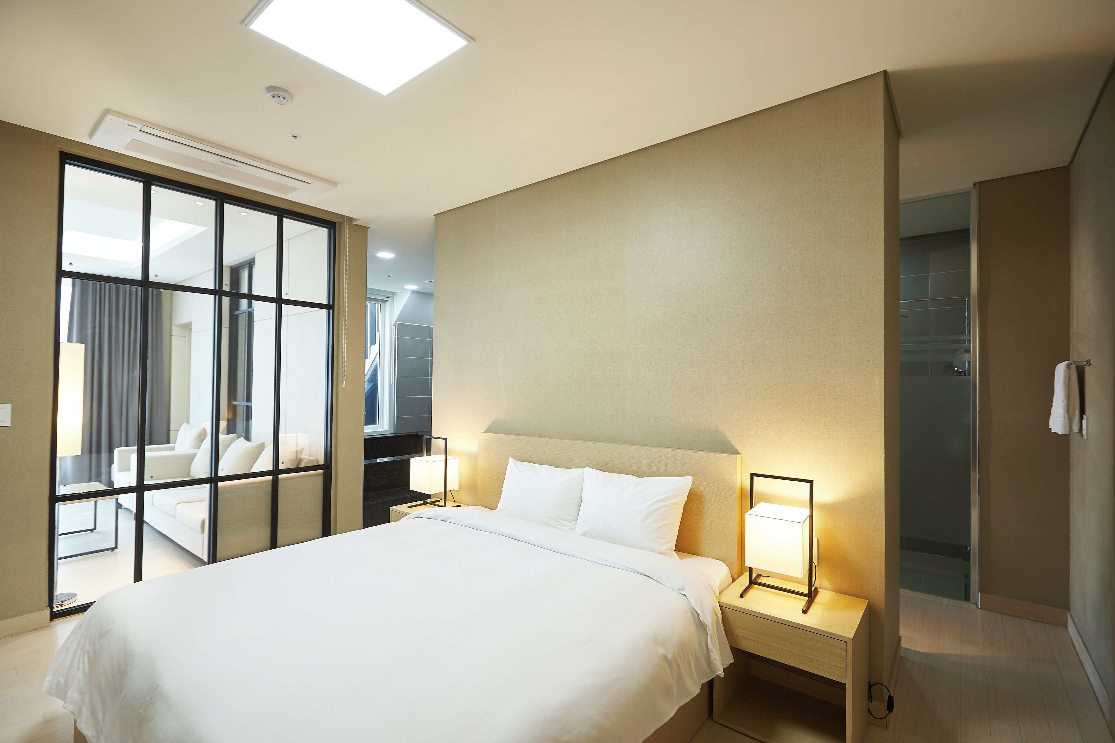 Quarto de hotel com uma cama grande, abajures, uma TV e vista para o exterior através de uma porta de correr.