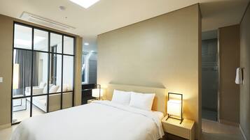 Quarto de hotel com uma cama grande, abajures, uma TV e vista para o exterior através de uma porta de correr.