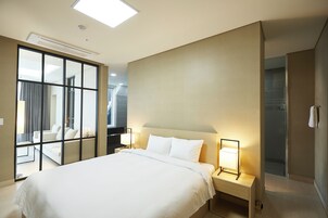 Quarto de hotel com uma cama grande, abajures, uma TV e vista para o exterior através de uma porta de correr.