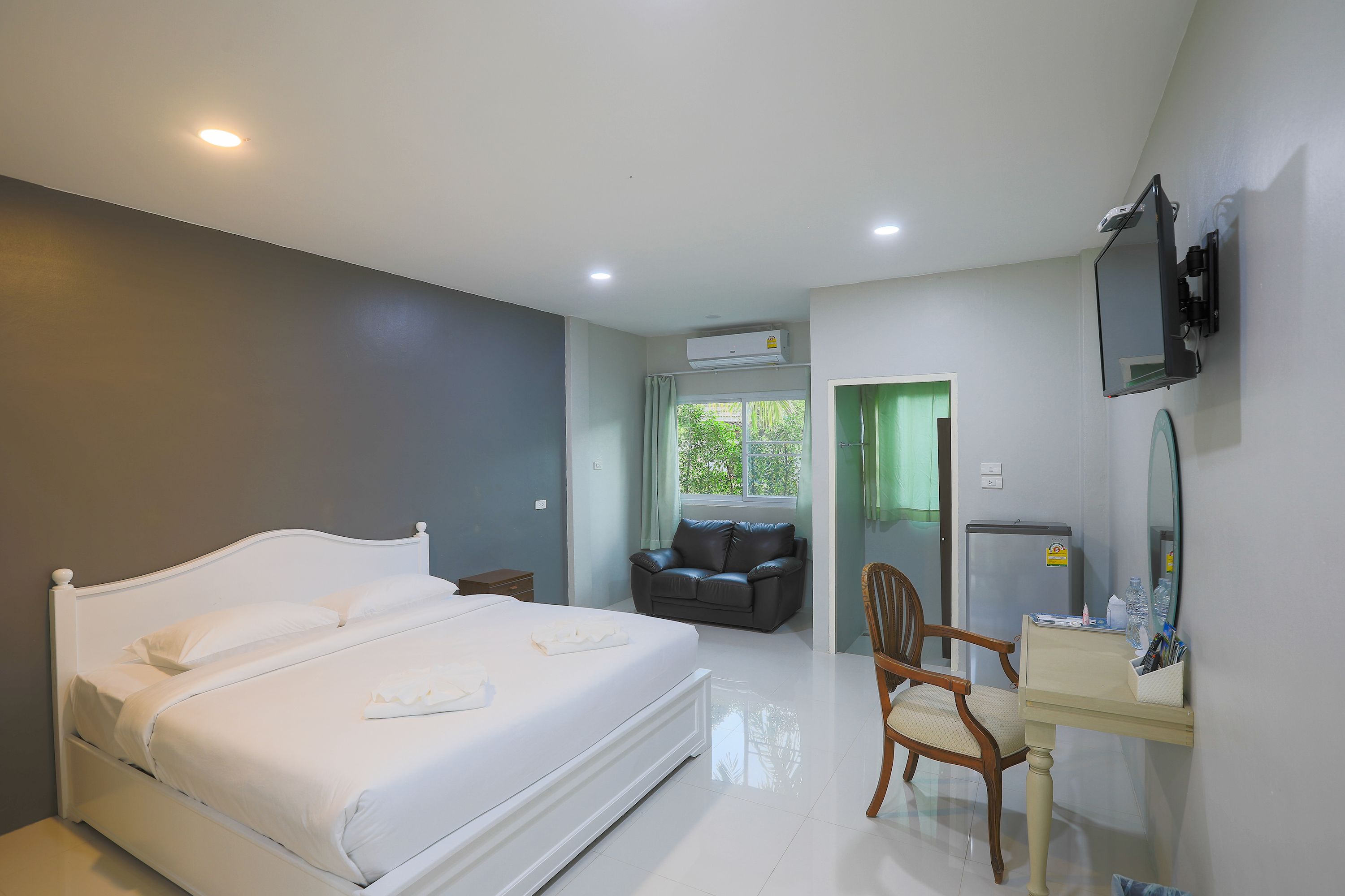 Quarto de hotel moderno com uma cama grande, uma escrivaninha com espelho e uma televisão.