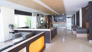 Um hall de hotel moderno com balcão de recepção, área de estar e kitchenette.