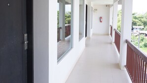 Um corredor com uma porta preta identificada com o número 307, um extintor de incêndio e uma varanda com guarda-corrimão.