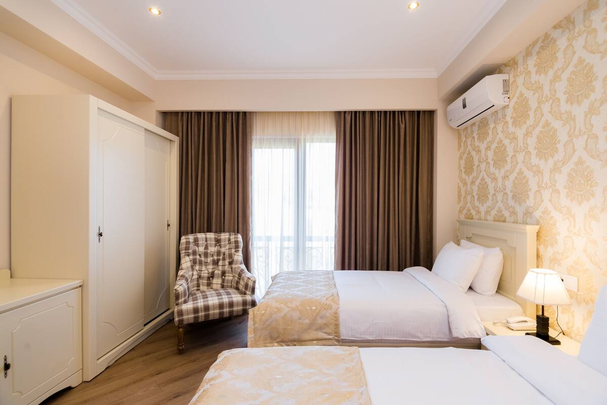 Quarto de hotel com cama, uma cadeira, guarda-roupa e ar condicionado.