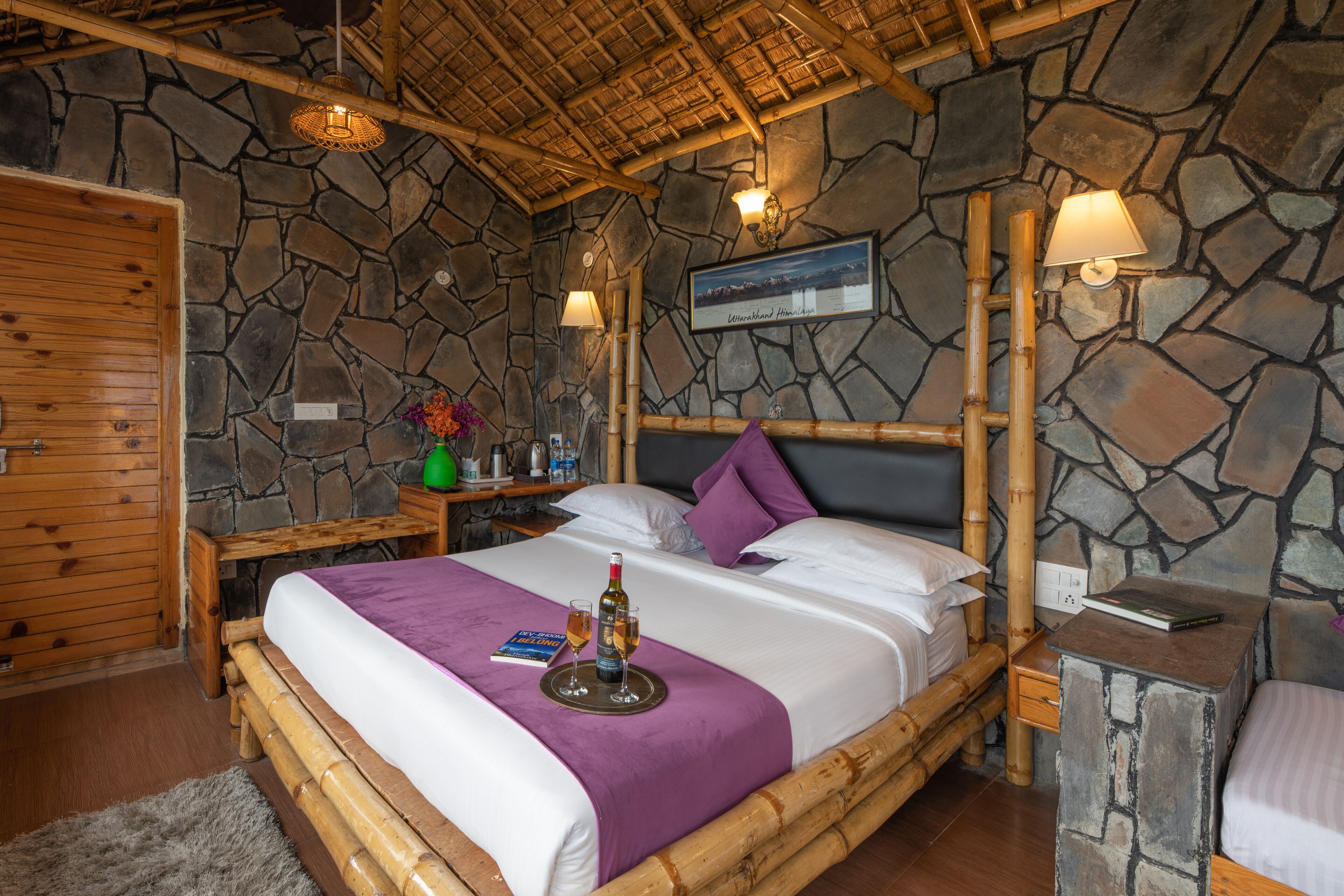 Quarto com parede de pedra, estrutura de cama de madeira e colcha roxa.