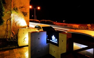 Uma área de estacionamento à noite, com uma placa indicando a entrada de uma garagem.