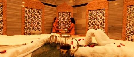 Um quarto de spa com uma mesa de massagem, um recipiente de vidro decorativo e paredes estampadas.