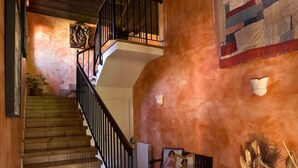 Escada com corrimão de madeira que leva a um patamar com um banco e objetos decorativos.